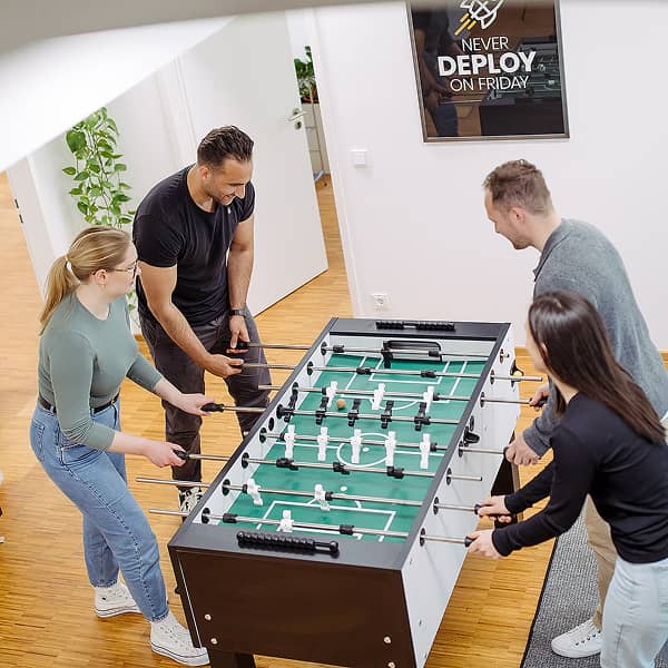 Vier mindtwo Teammitglieder spielen gemeinsam Tischkicker im Büro